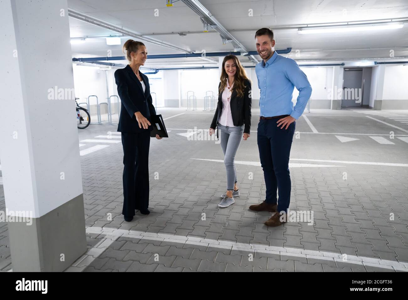 Couple Looking At Parking Place In Garage With Agent Stock Photo - Alamy