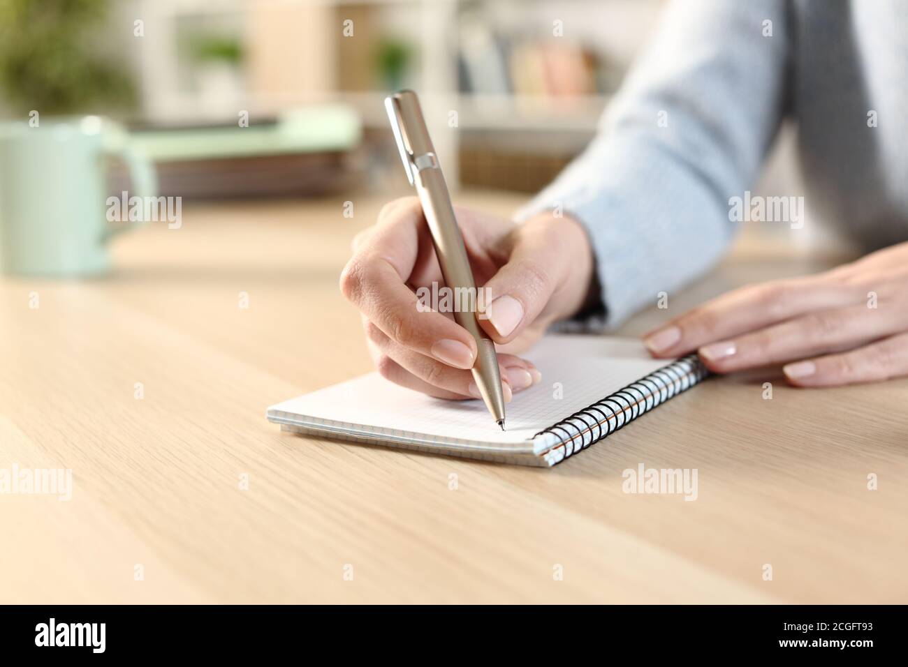 Close up of a woman hand witing on a notepad sitting on a desk at home ...