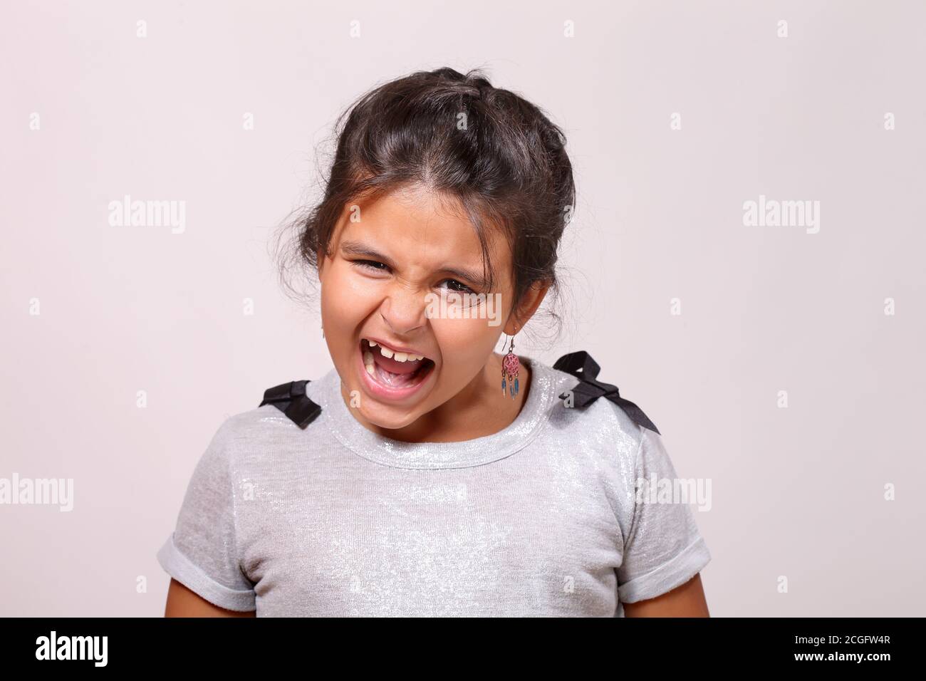 Portrait of an angry seven years girl screaming at camera. Studio shot ...