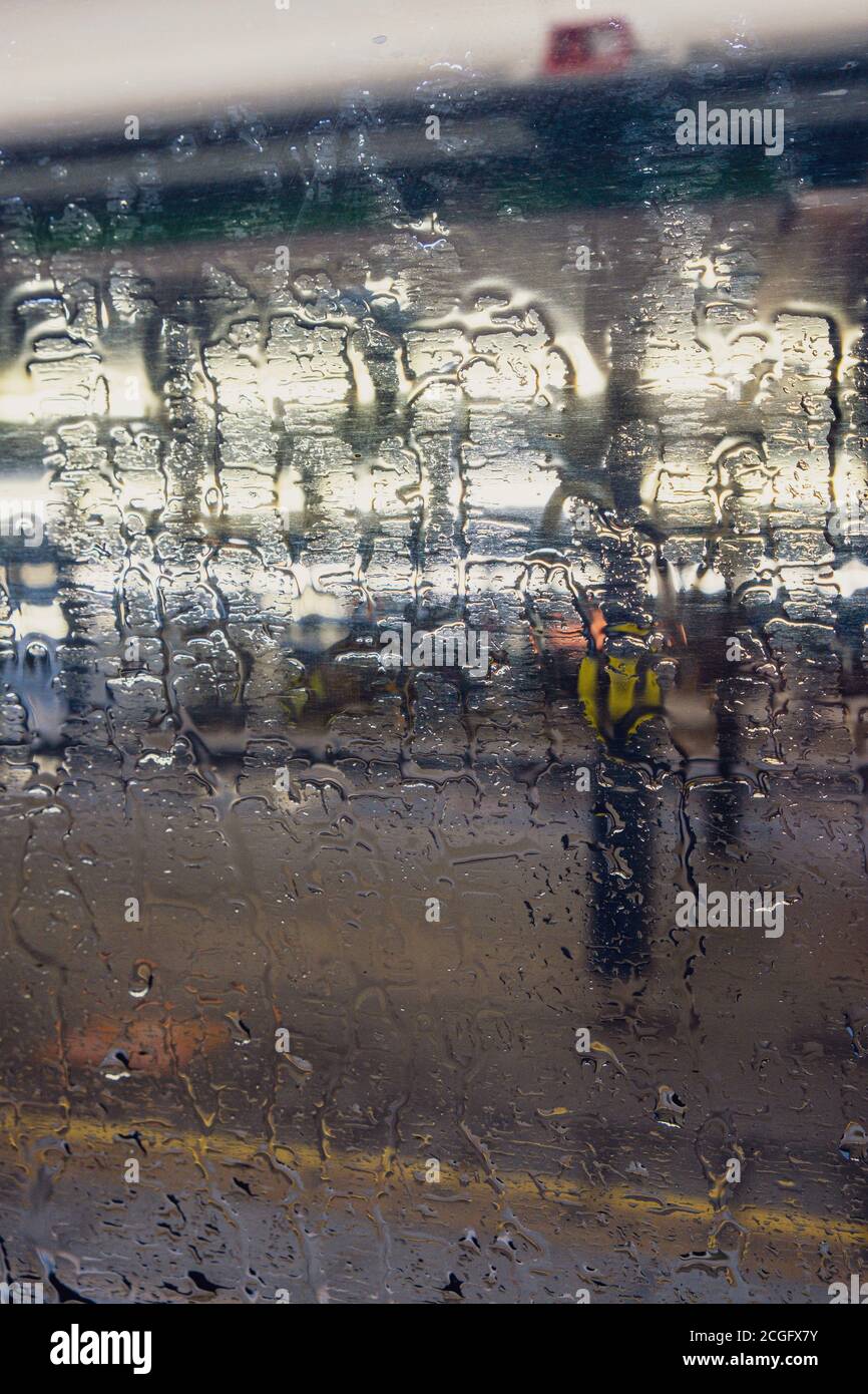 Rain on a train window obscuring the view of station, fields and ...