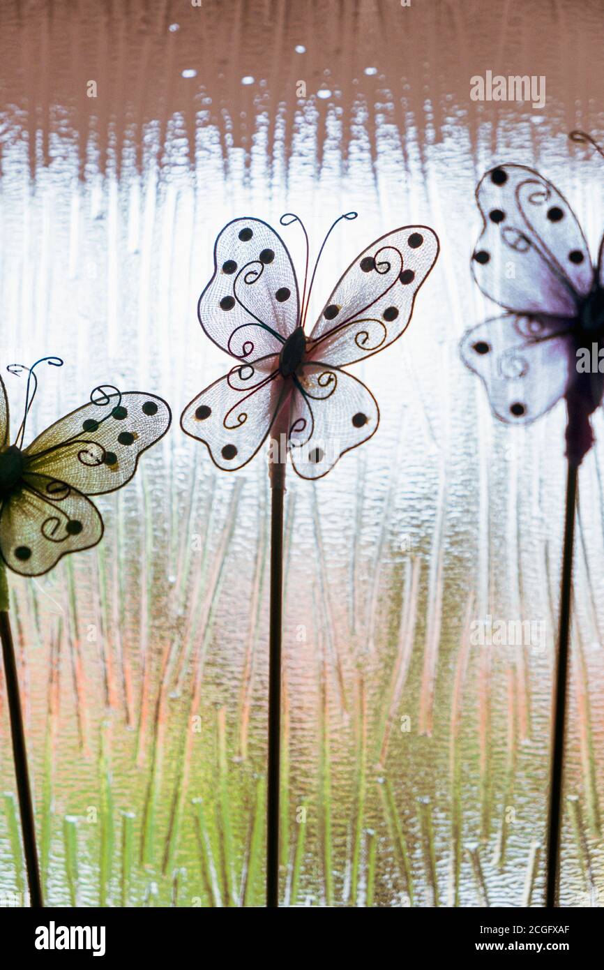 Threee delicate butterflies made from wire and material on sticks ...