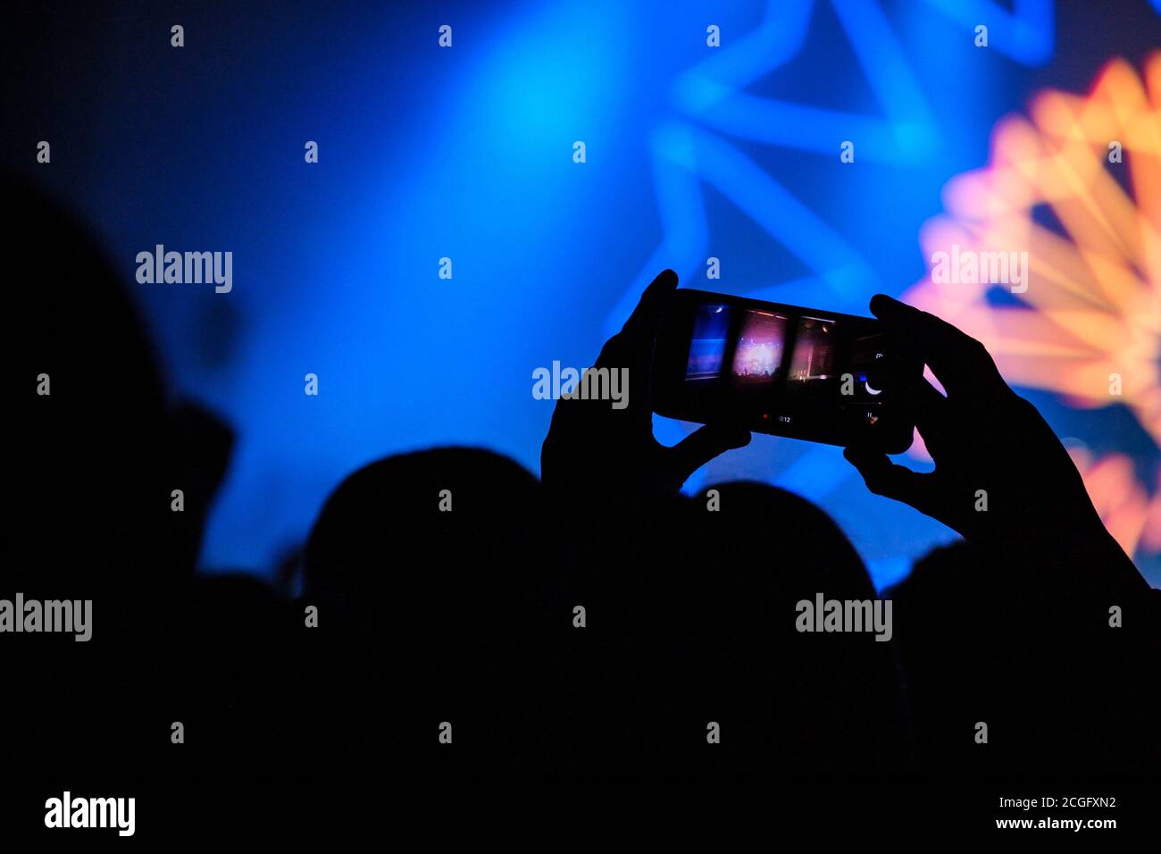 People recording and taking photos of a DJ at a night club hold their ...