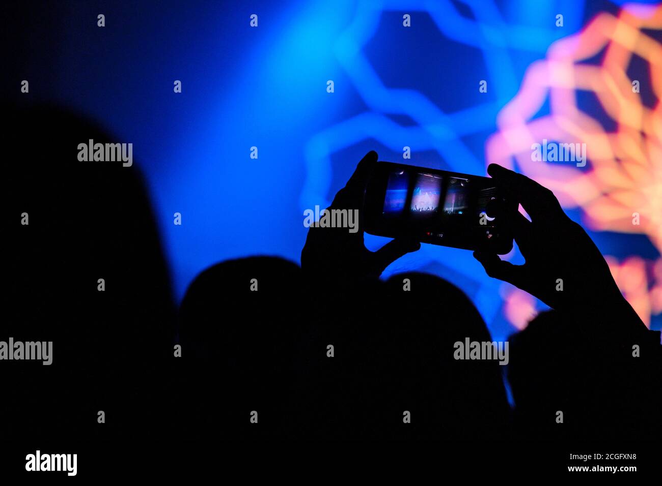 People recording and taking photos of a DJ at a night club hold their ...