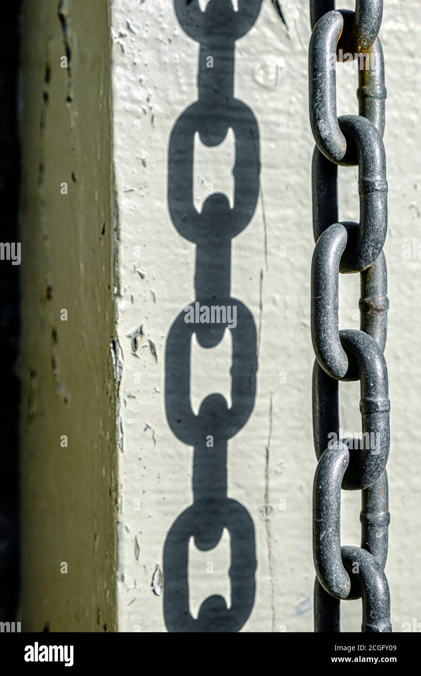 A thick metal chain hanging from a gate post whre it has been left ...
