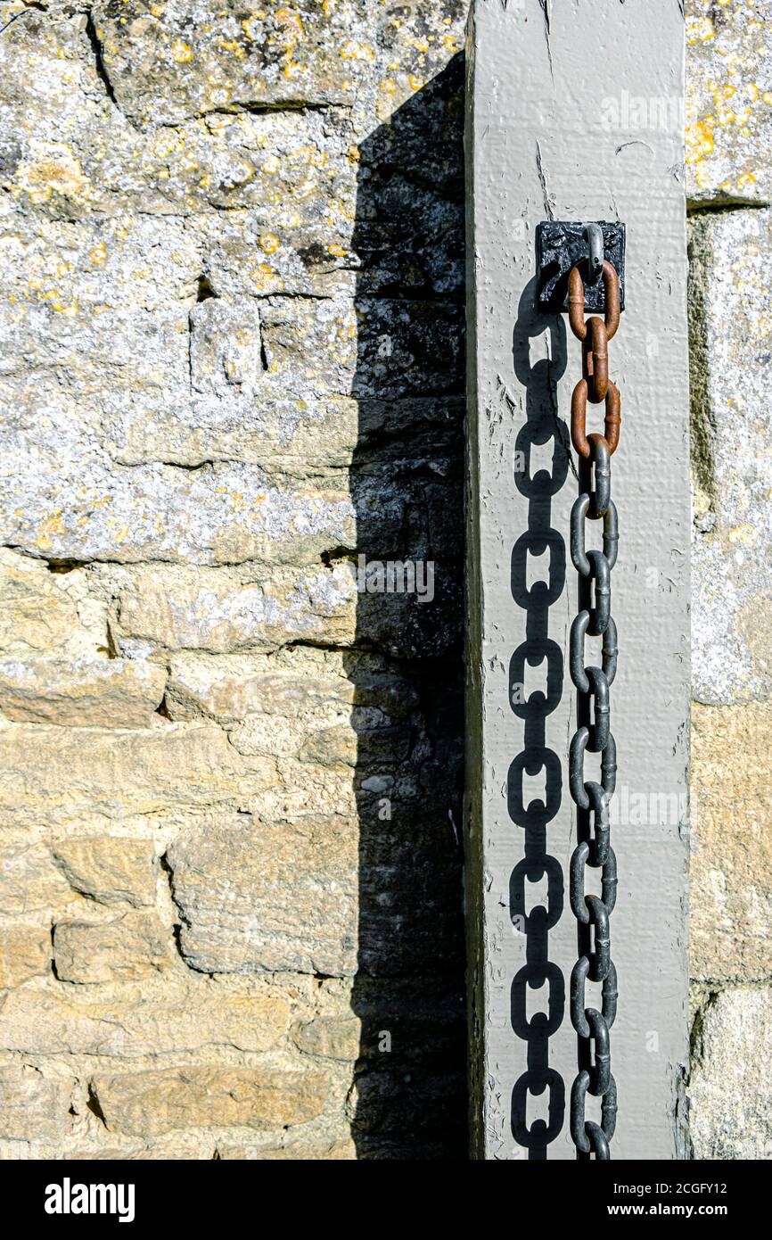 A thick metal chain hanging from a gate post whre it has been left ...