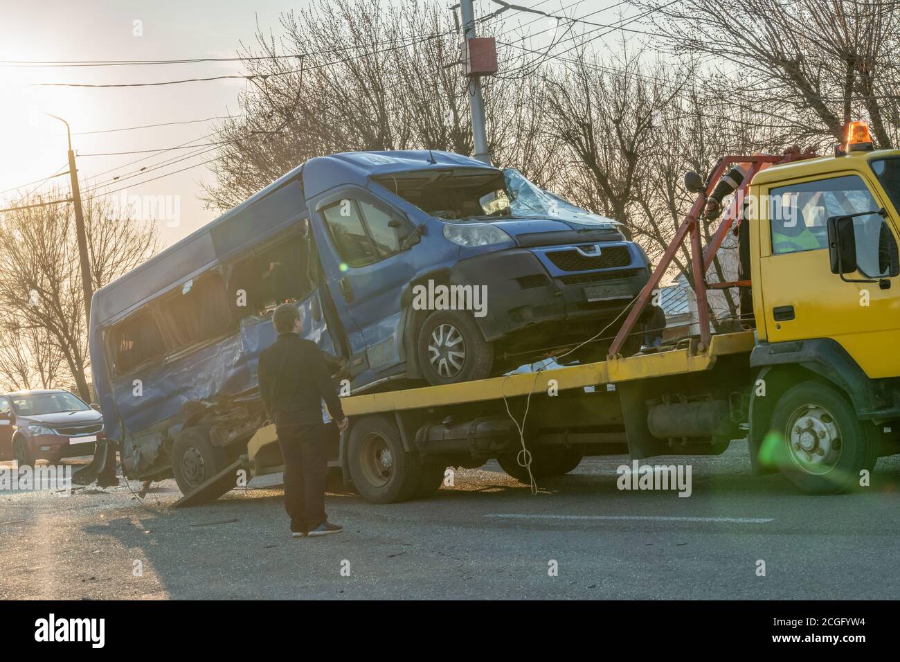 Loading a broken blue minibus on a yellow tow truck in the middle of ...