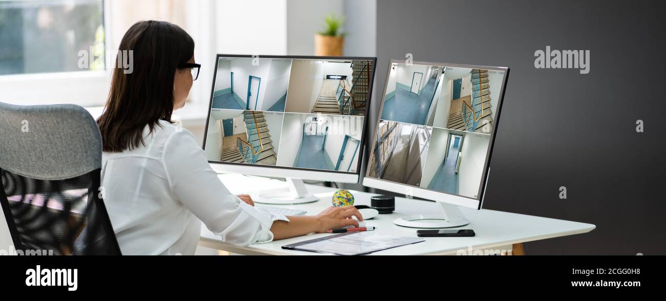 Businesswoman Watching CCTV Footage Of Office Interior On Computer At ...