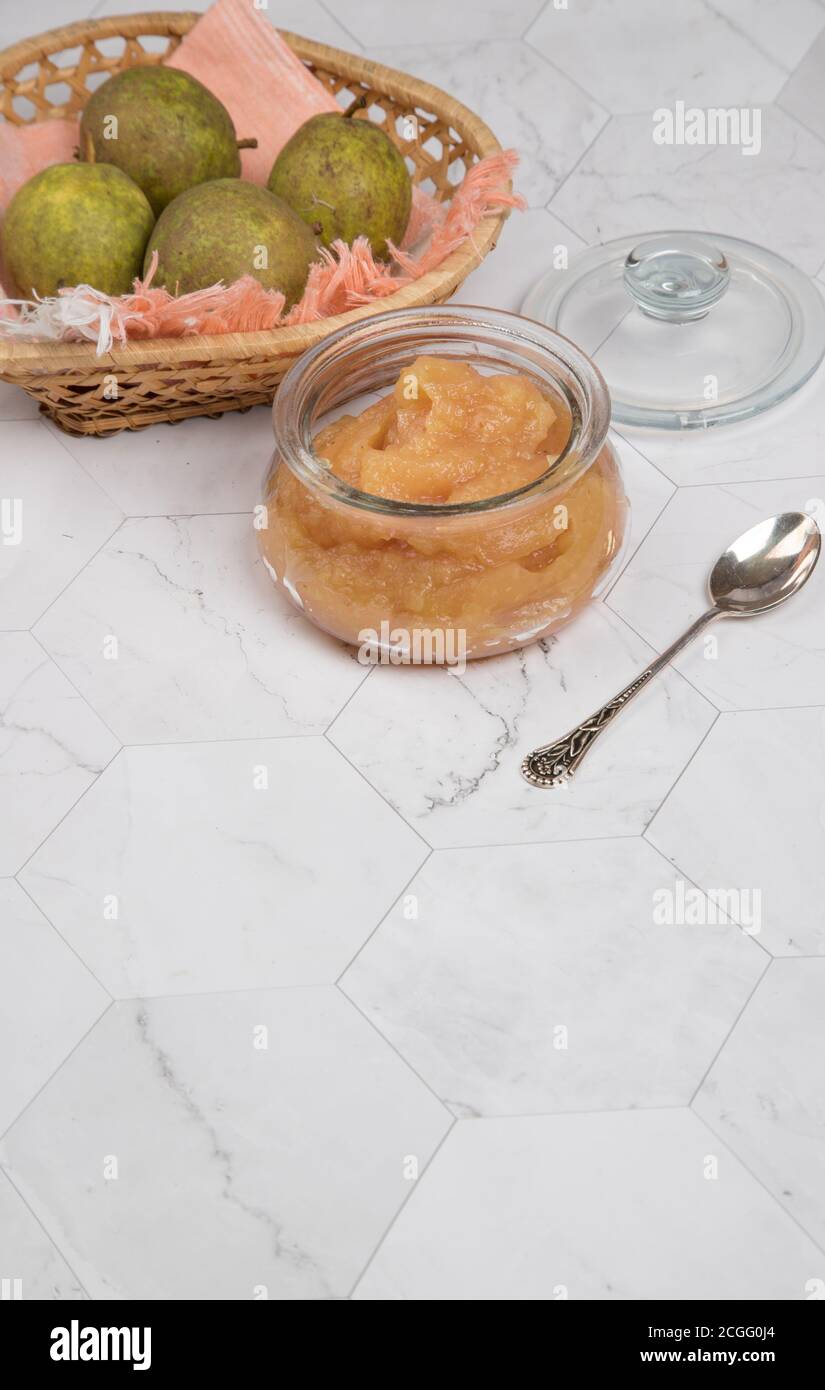 Glass jar with mashed pears and fresh pears in a wicker plate on a ...