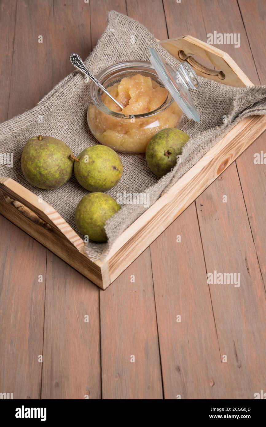 Wooden tray with a jar of mashed pears and fresh pears on a light ...