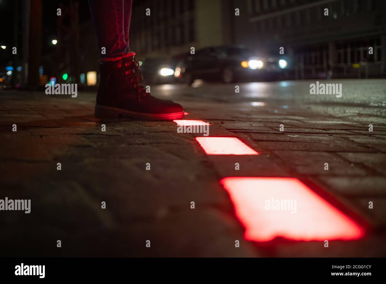 girl's feet in boots are standing on a pedestrian crossing and waiting ...