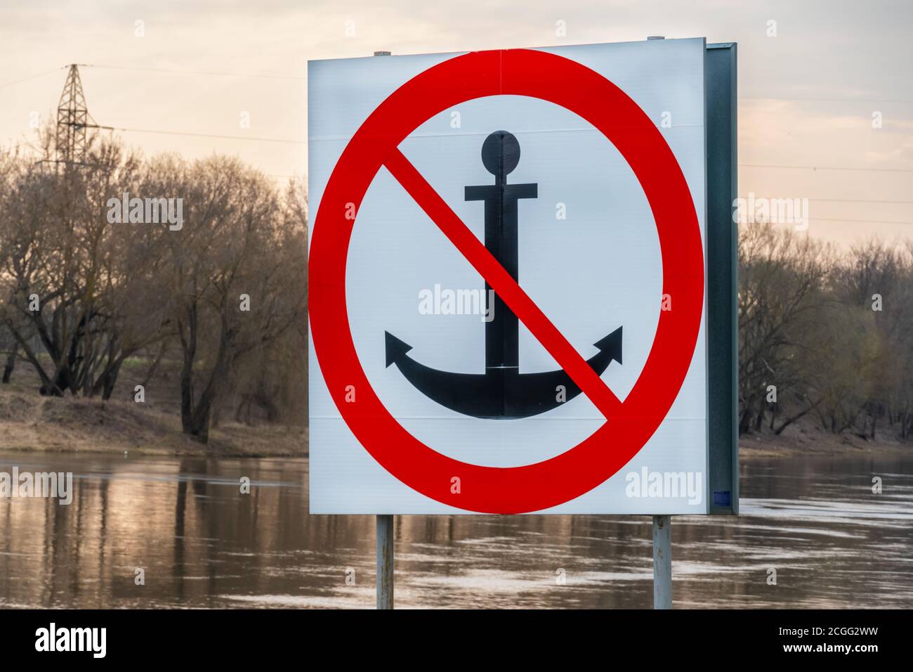 A sign near the river DO NOT DROP ANCHOR against the sunset sky. Close ...
