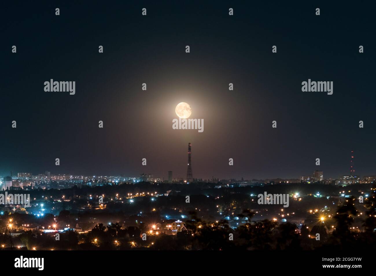 Bright full moon shining on dark night sky above colorful city lights ...