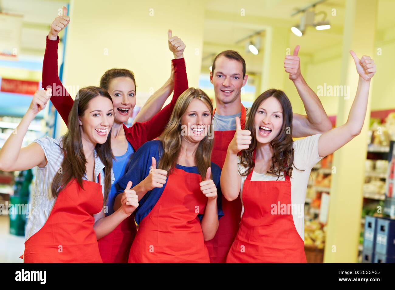 The winning team in the supermarket holds out the thumbs up, laughing ...