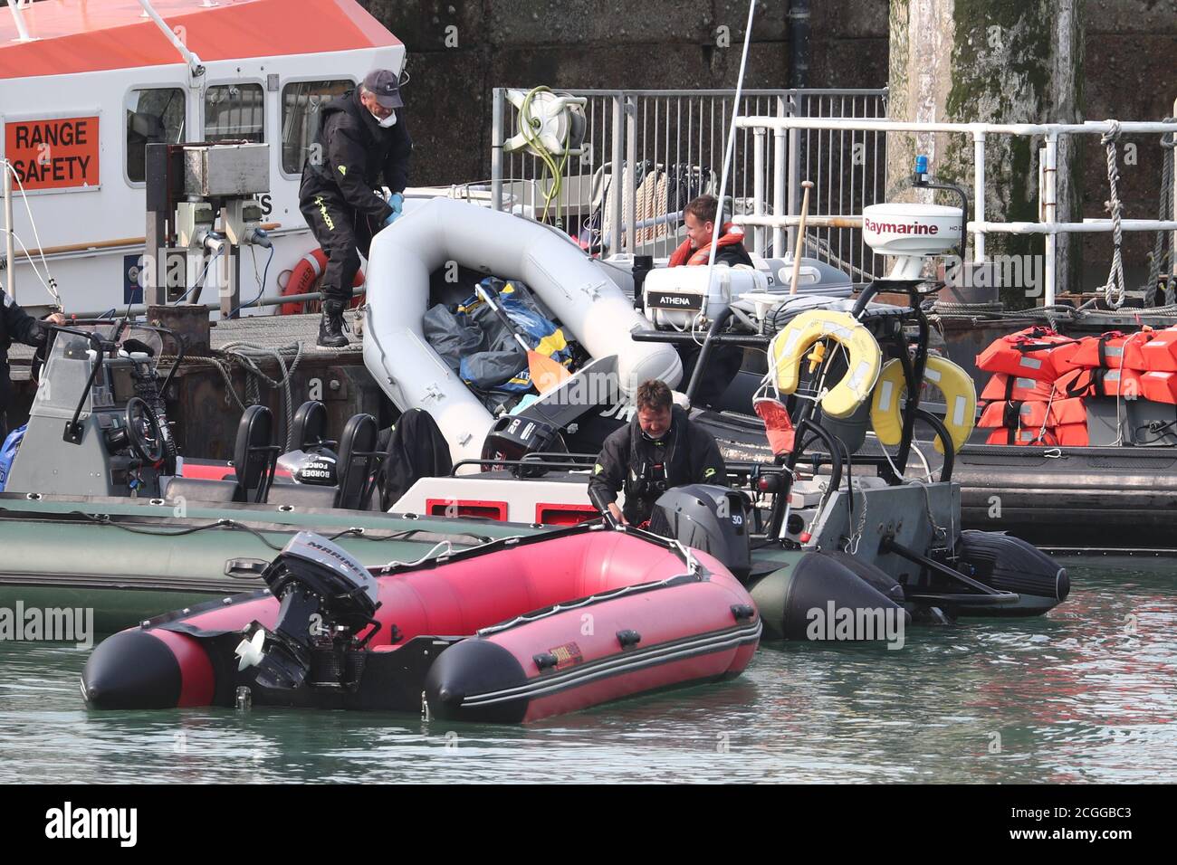 A Border Force officer tows in dingys into Dover, Kent, used by ...