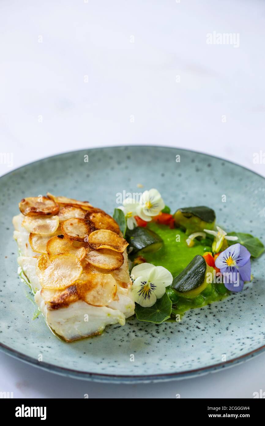 White fish fillet with potato scale, pea puree and summer vegetable ...