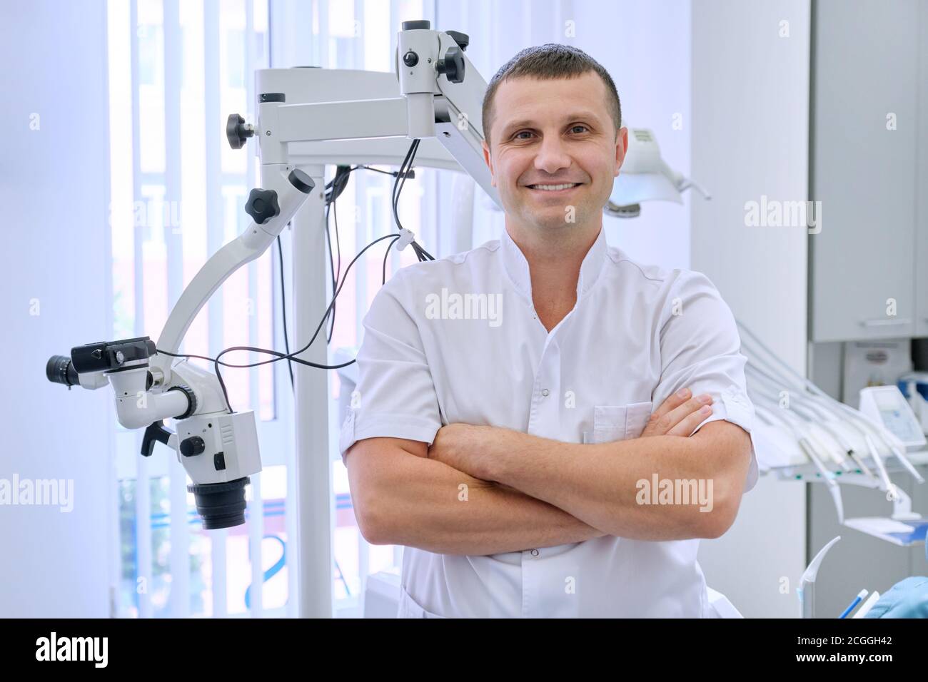 Portrait of confident friendly male dentist with crossed arms Stock ...