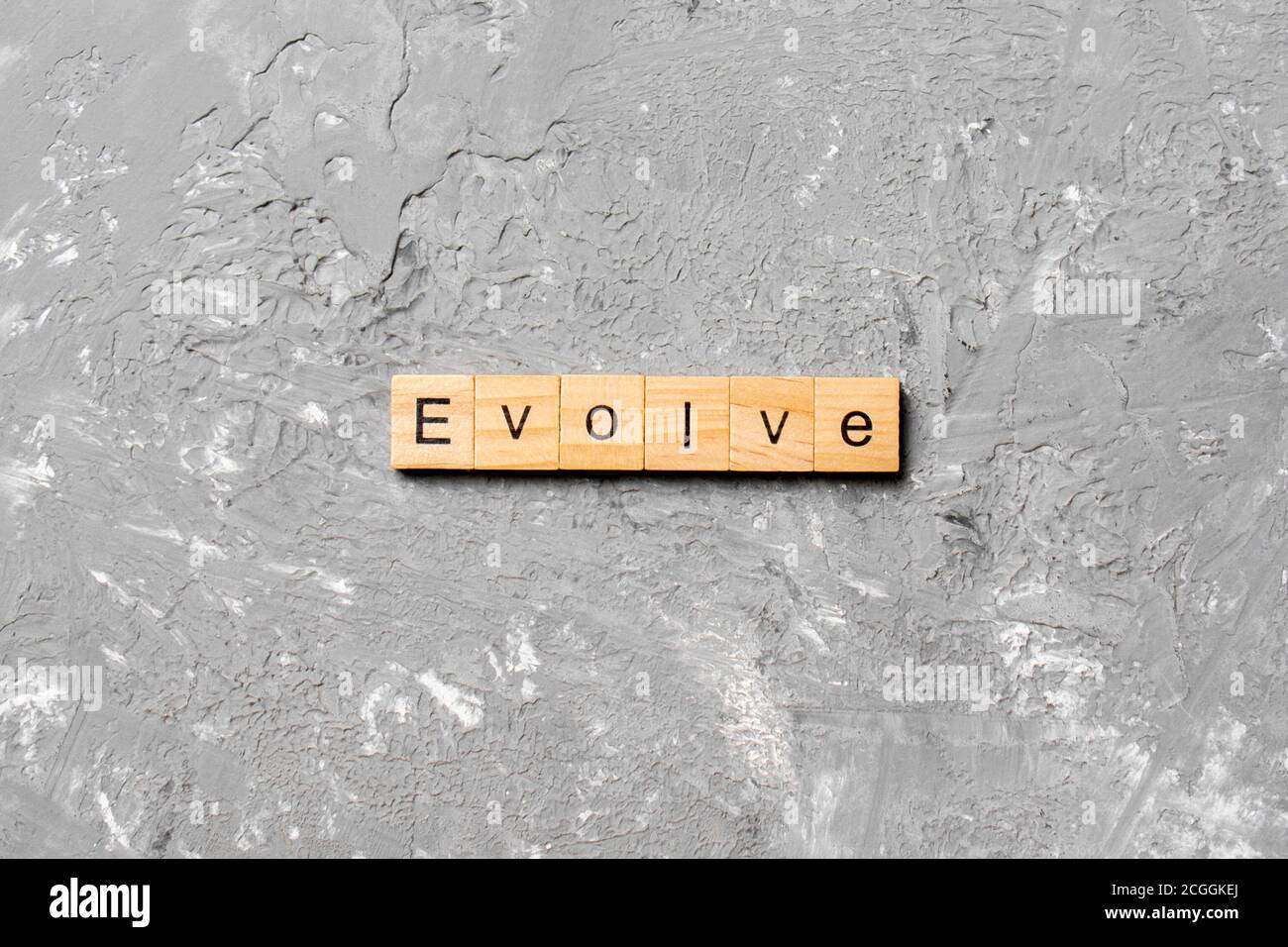 EVOLVE word written on wood block. EVOLVE text on cement table for your ...