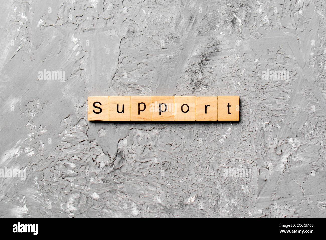 Support word written on wood block. Support text on cement table for ...