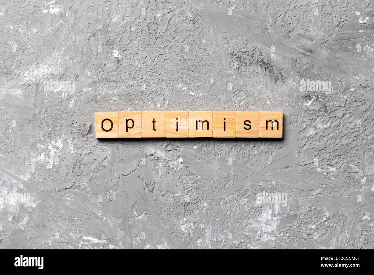 Optimism word written on wood block. Optimism text on cement table for ...