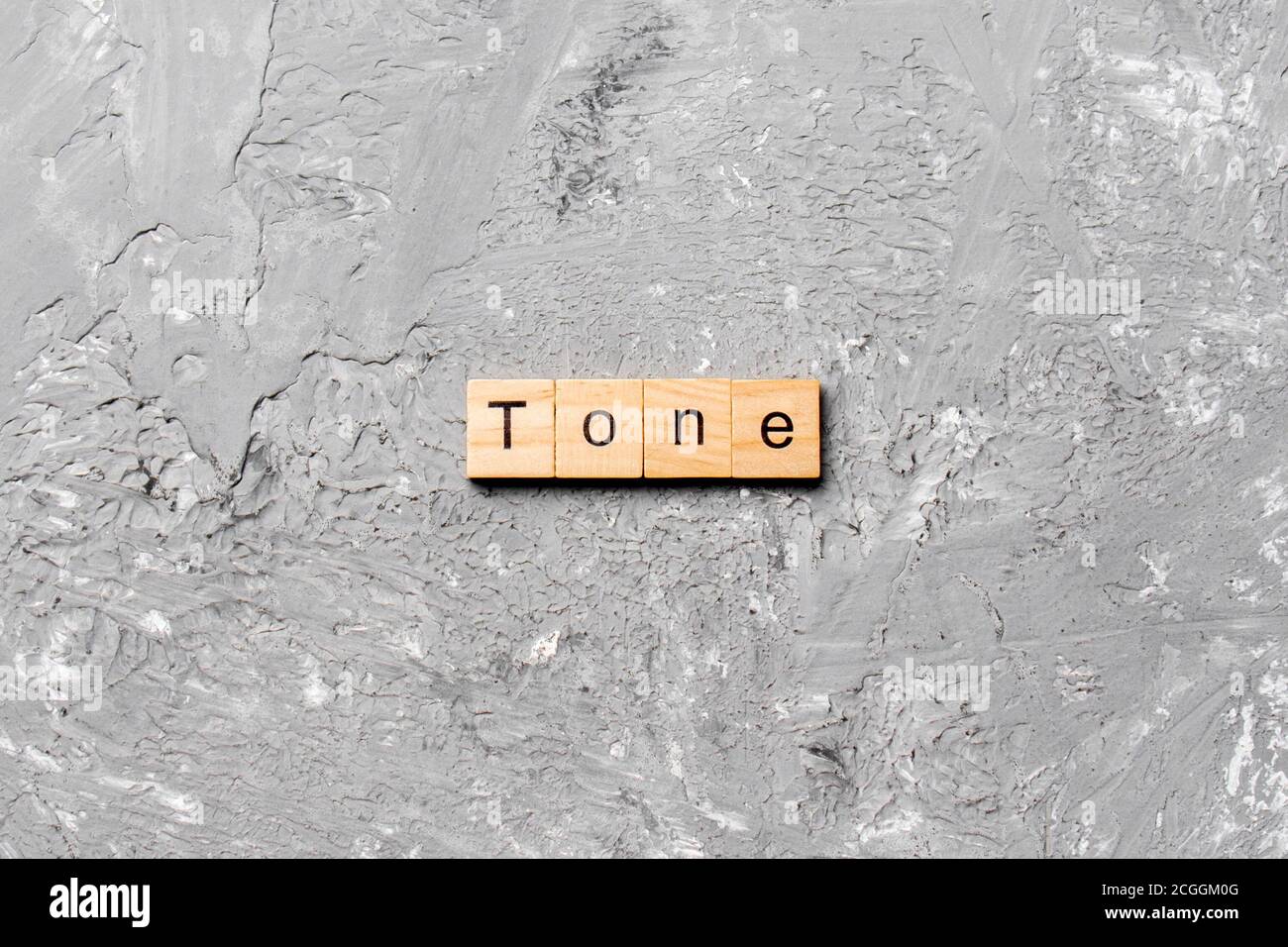 tone word written on wood block. tone text on cement table for your ...