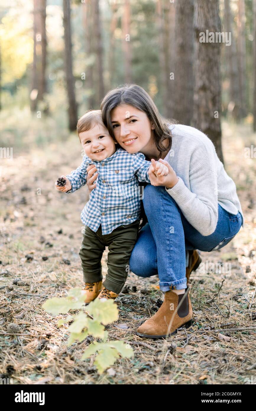 Outdoor autumn portrait of young pretty woman mother posing in autumn pine forest with her ...