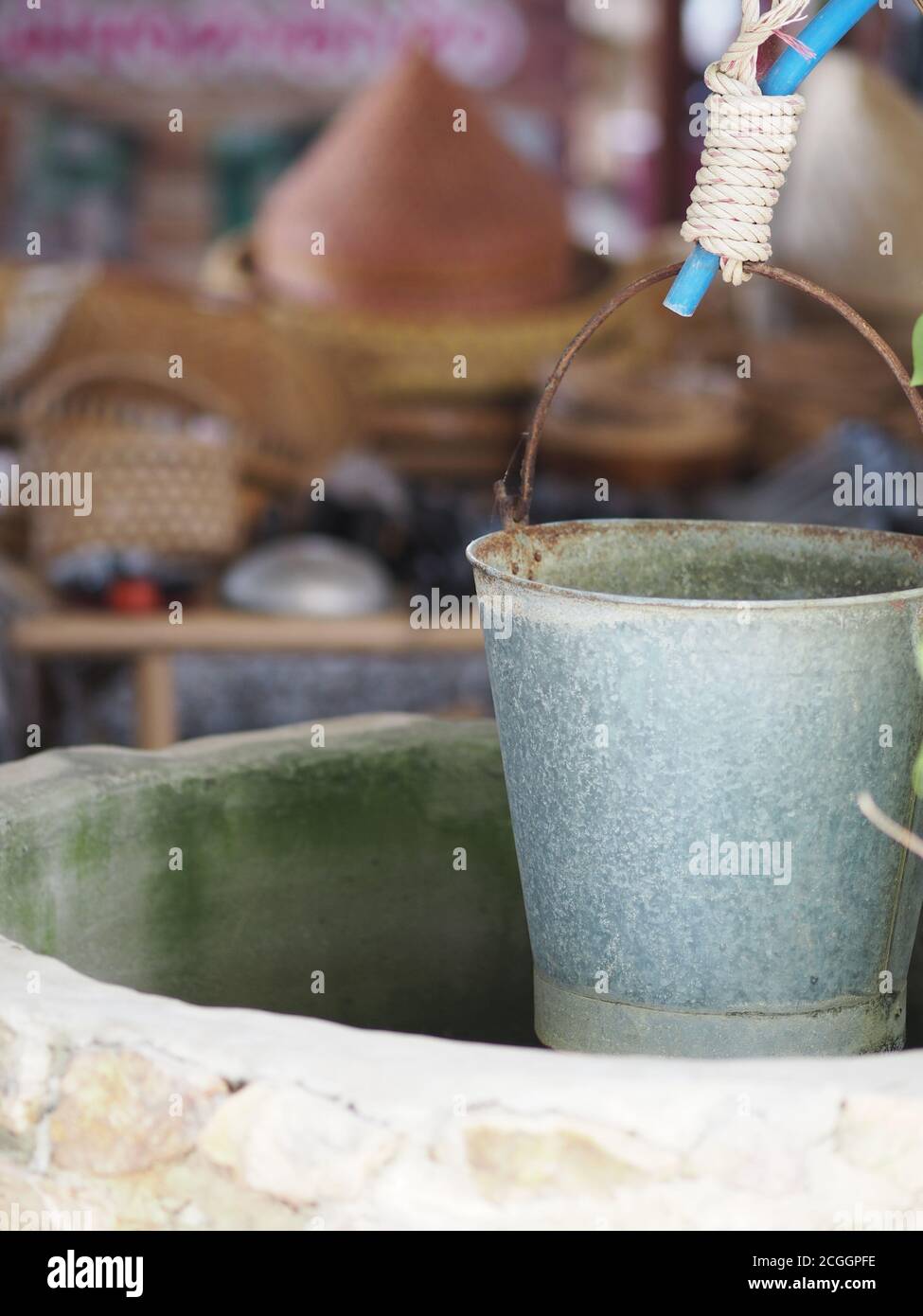 Zinc water bucket hang by hemp rope on Artesian well made of cement ...