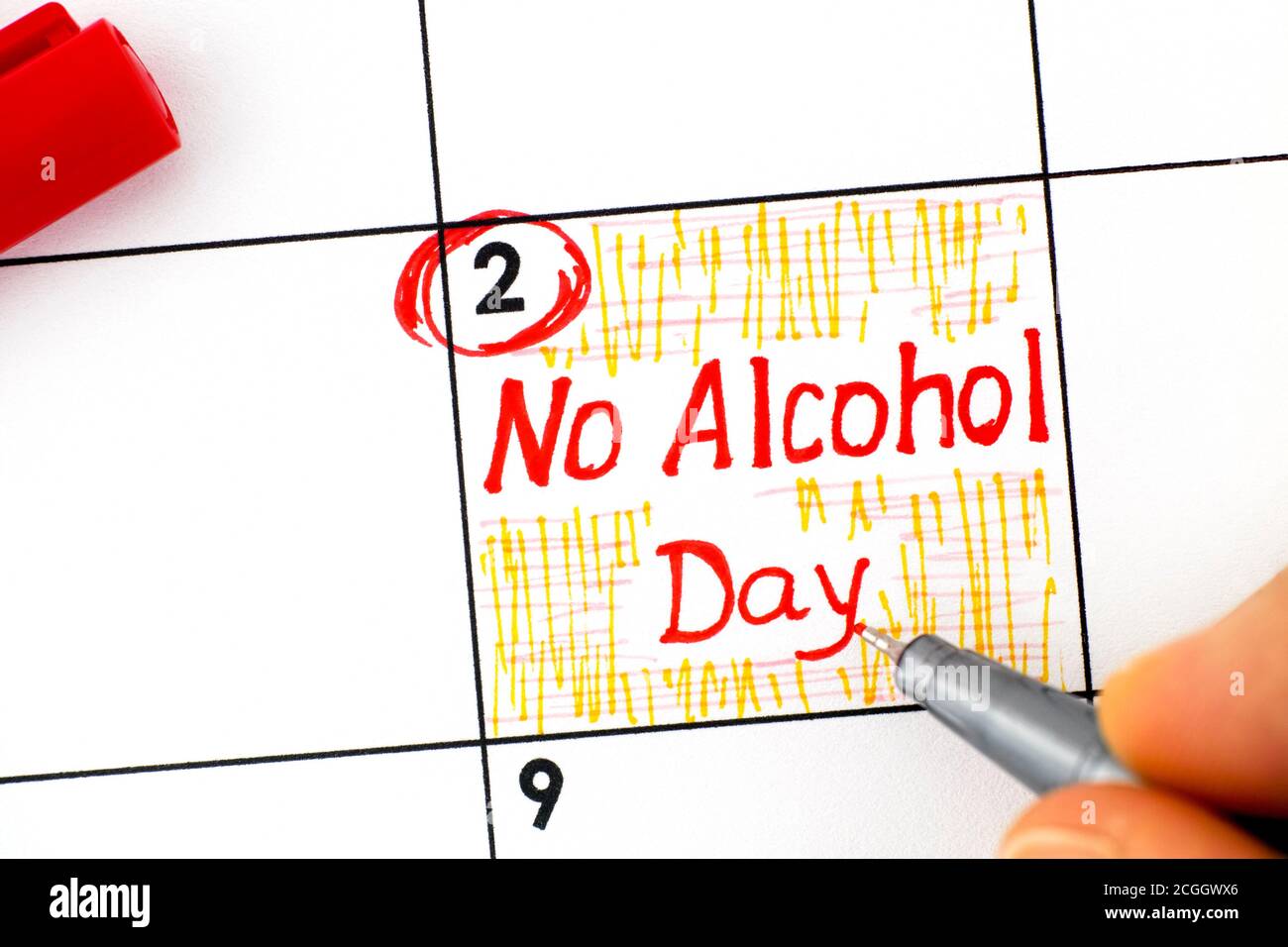 Woman fingers with pen writing reminder No Alcohol Day in calendar ...
