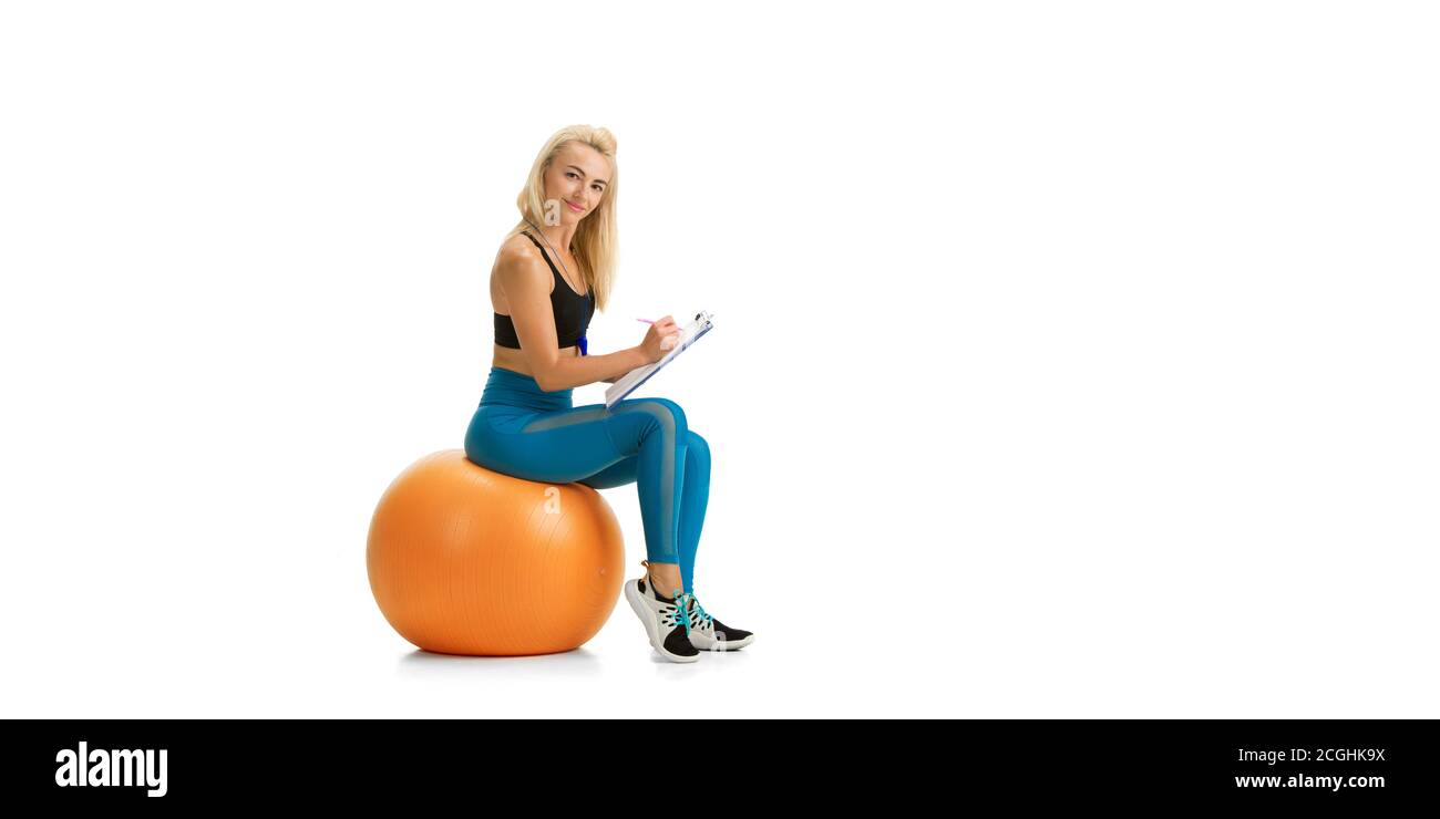 Making notes on fit ball. Beautiful female fitness coach practicing ...