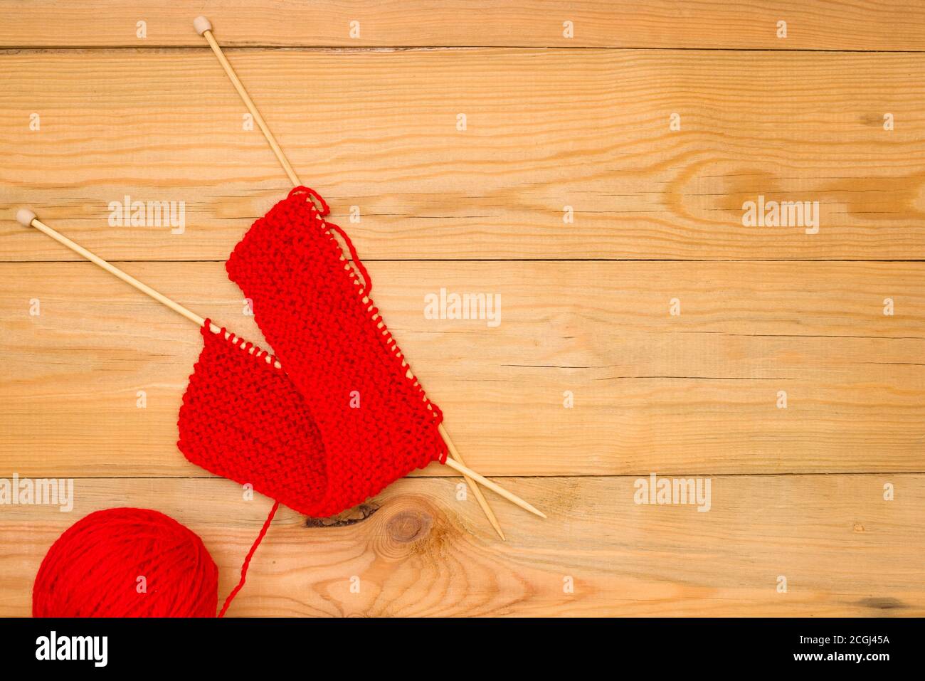 Red ball of yarn with spokes on a wooden background, free space for ...