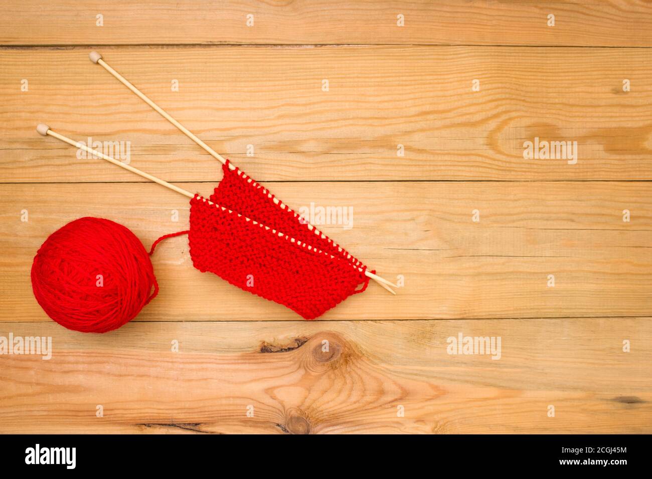 Red ball of yarn with spokes on a wooden background, free space for ...