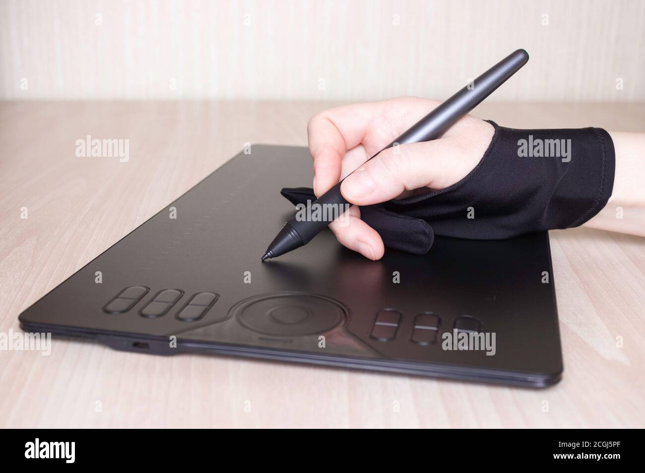 A woman's hand in a special glove draws on a graphics tablet. Side view ...