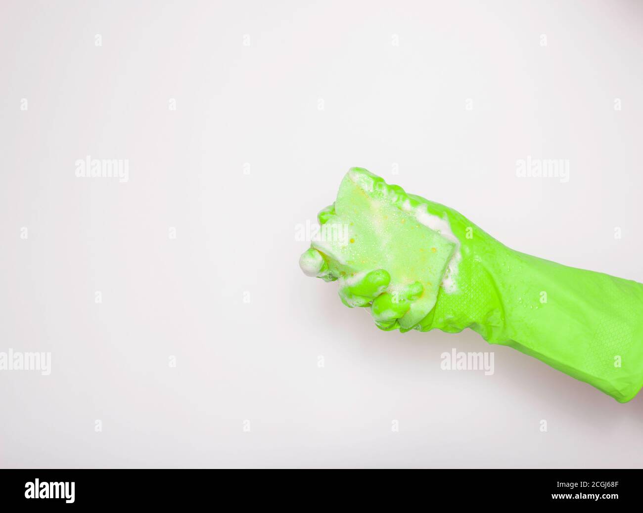 Hand in an green rubber glove with an green sponge and foam on a white ...