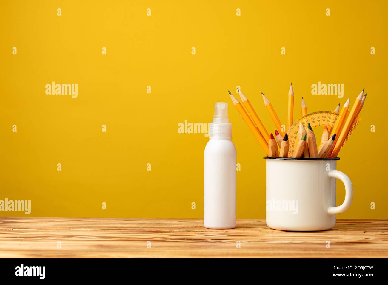 Back to school concept with stationery in cup and hand antiseptic spray ...