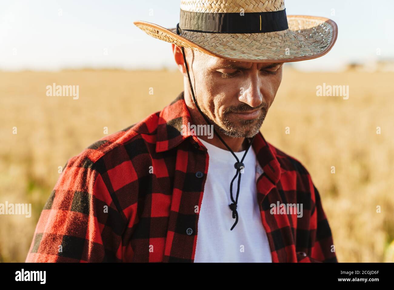 Image of unshaven adult man in straw hat looking downward while ...