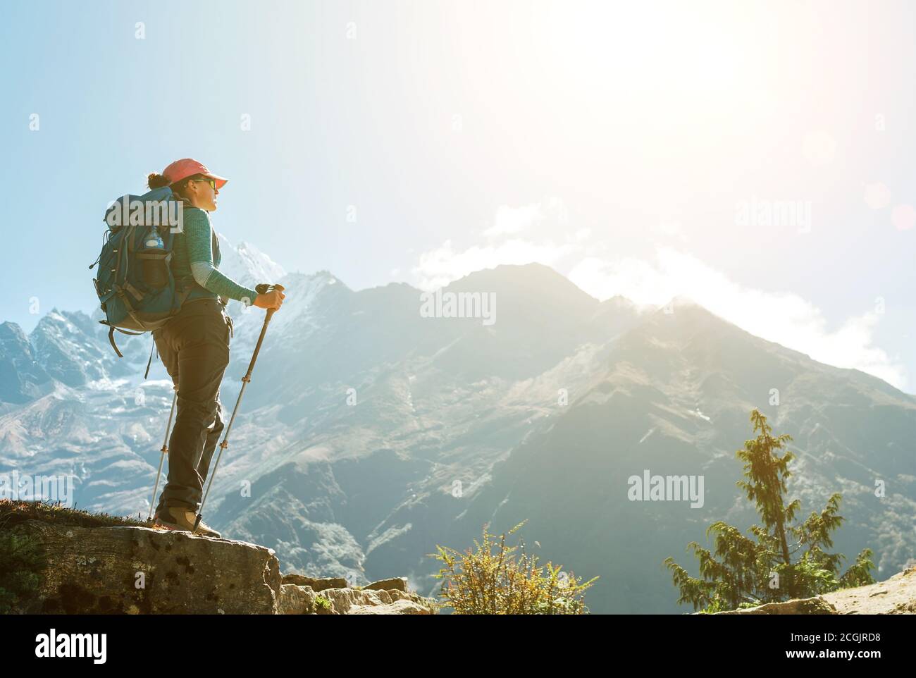 Young hiker backpacker female using trekking poles enjoying mountain ...
