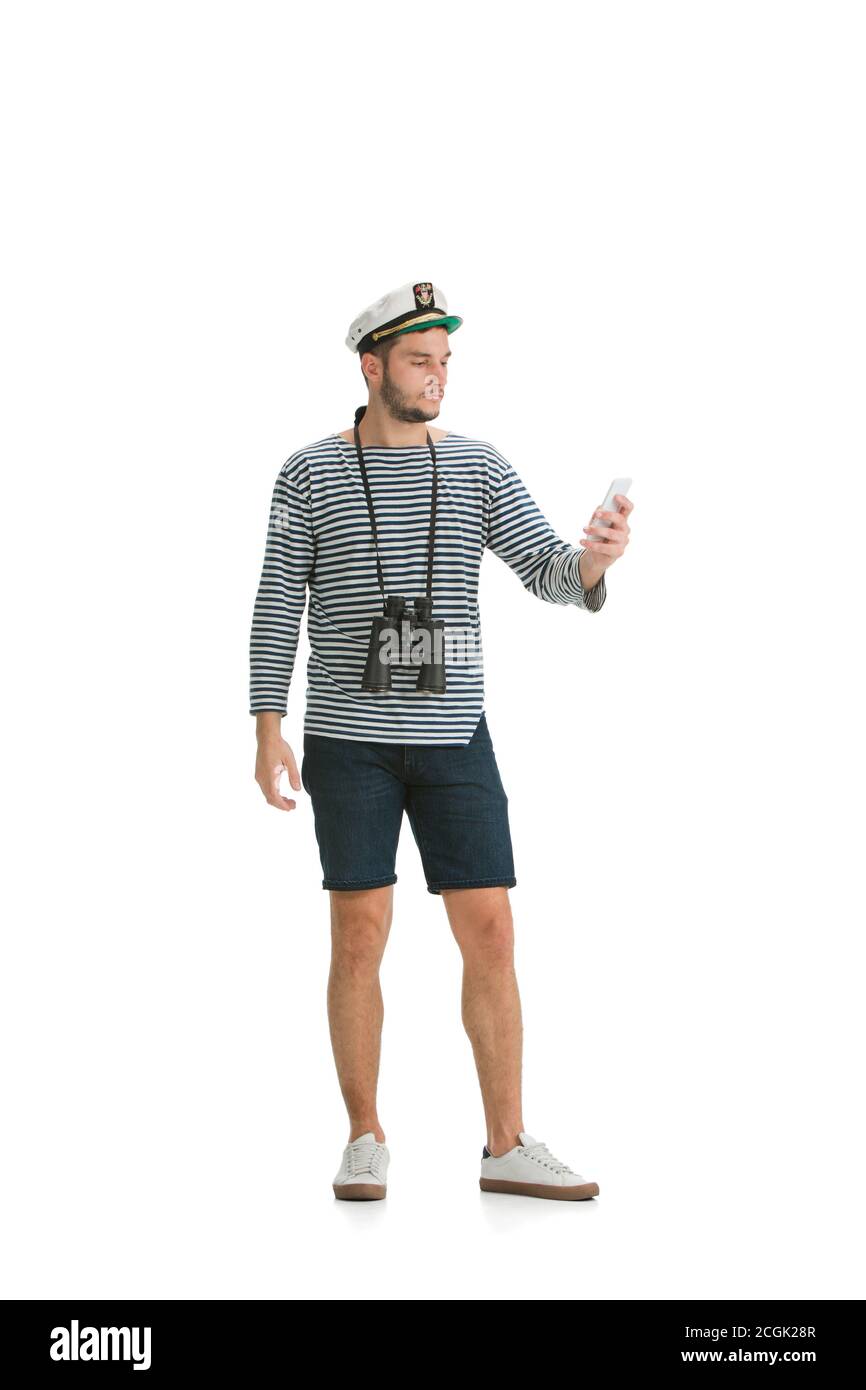 Scrolling phone. Caucasian male sailor in uniform on white studio ...