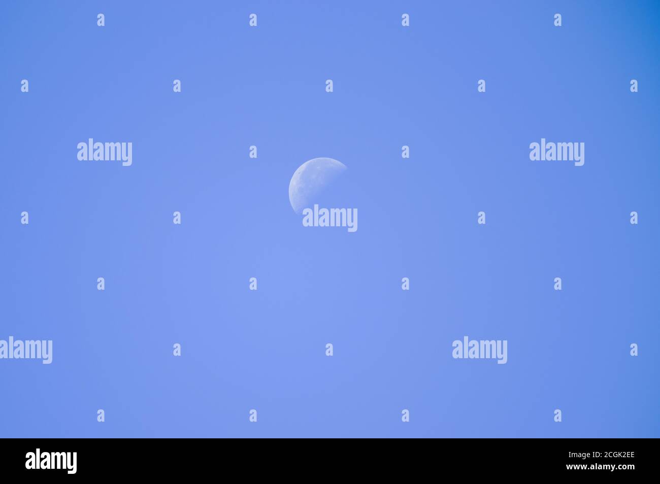 Last quarter moon in daytime with a clear blue sky Stock Photo - Alamy