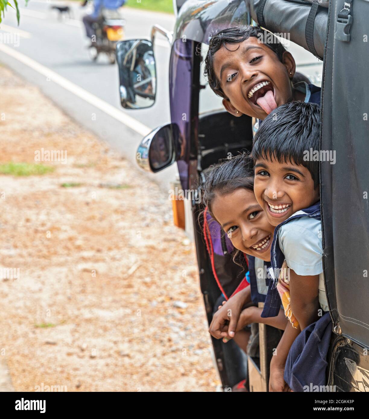 Three happy, smiling and joking pupils, riding home by tuk tuk, after ...