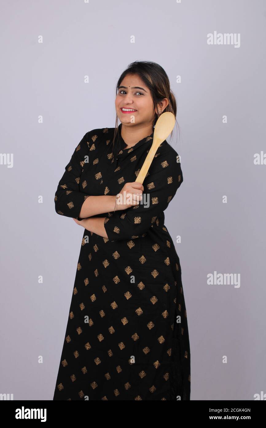 Beautiful Indian girl or woman or home maker holding serving spoon or ...