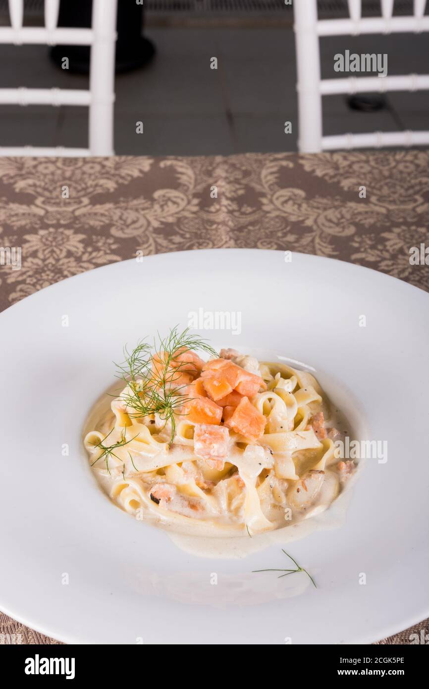 Delicious pasta served with salmon on a table by the pool Stock Photo ...