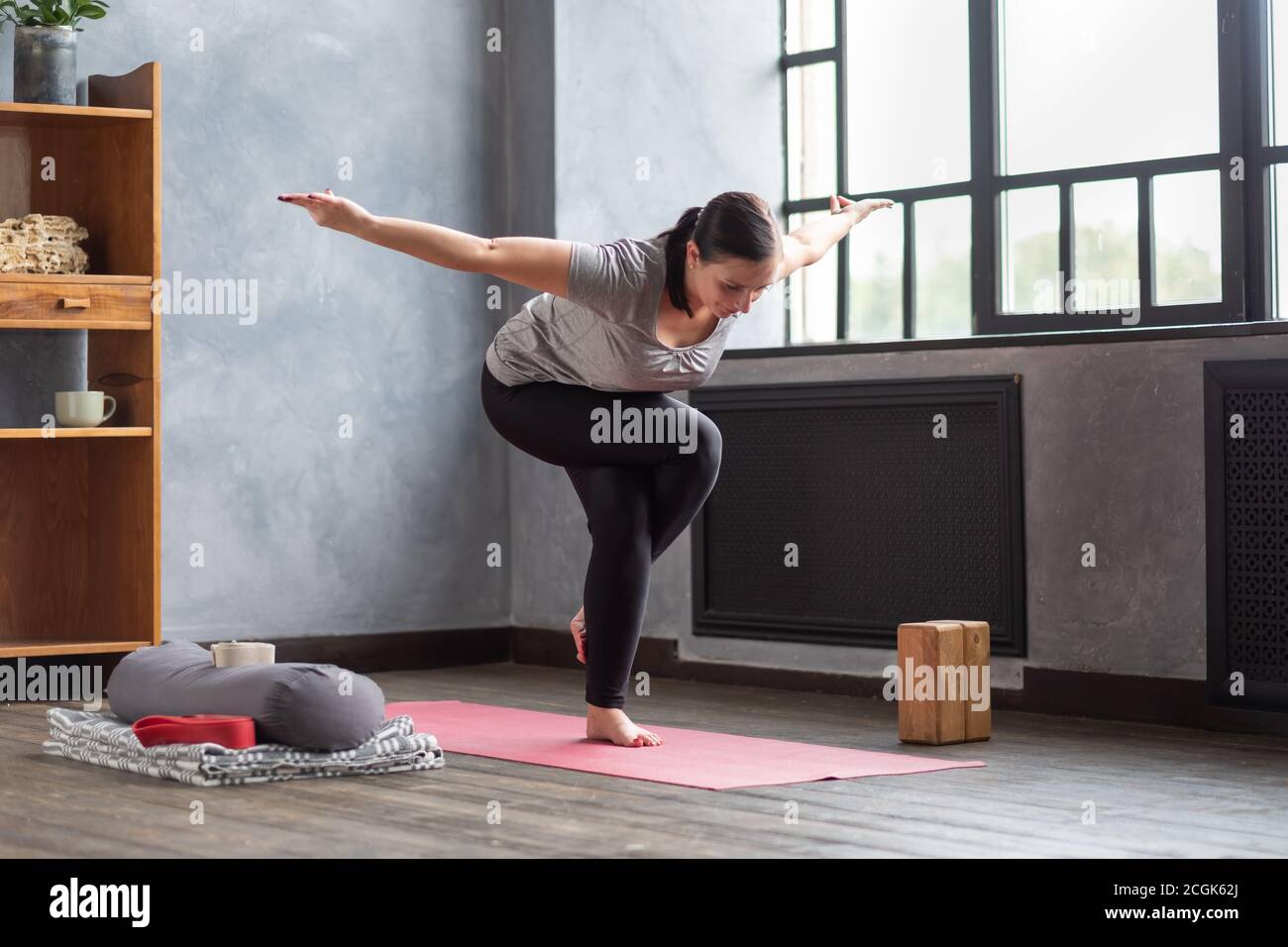 Young woman practicing yoga, standing in Eagle exercise, Garudasana ...
