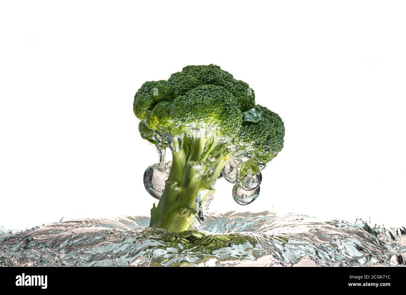 Green broccoli falling in water with splash on white with air bubbles ...