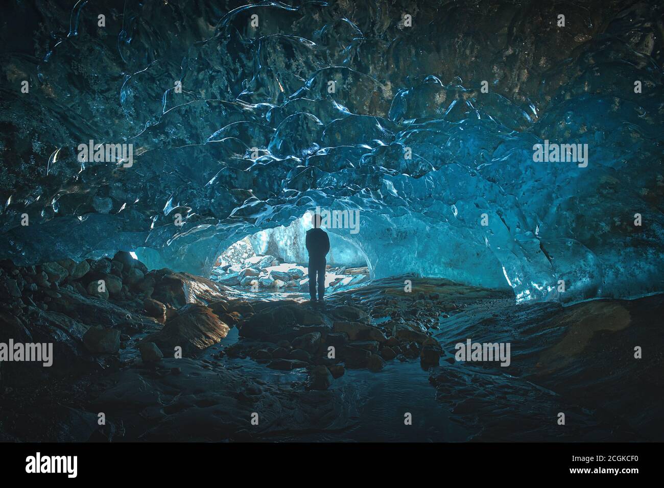 Person ice cave in a mountain glacier, a column of the purest ice hangs ...