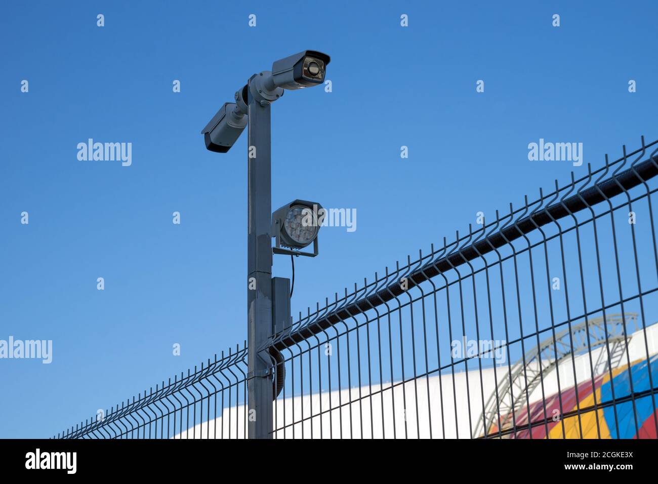 The surveillance camera is attached to the metal fence of the protected ...
