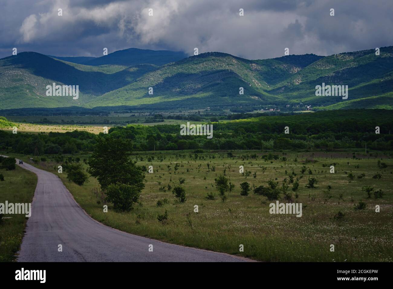 Beautiful country valley road before a thunderstorm at sunset. Mountain ...