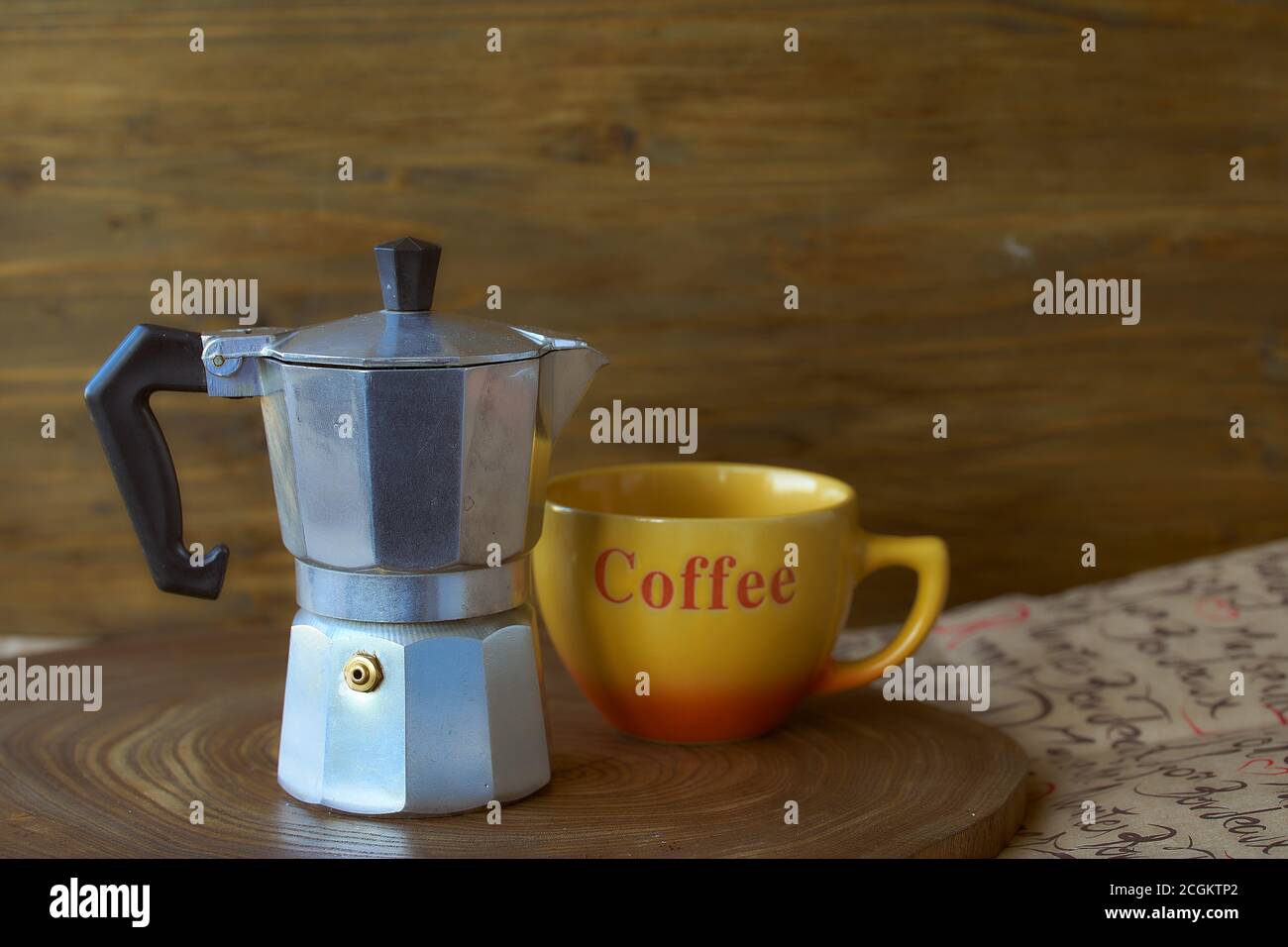 Geyser coffee maker on a wooden tray. There's a cup of coffee next to ...