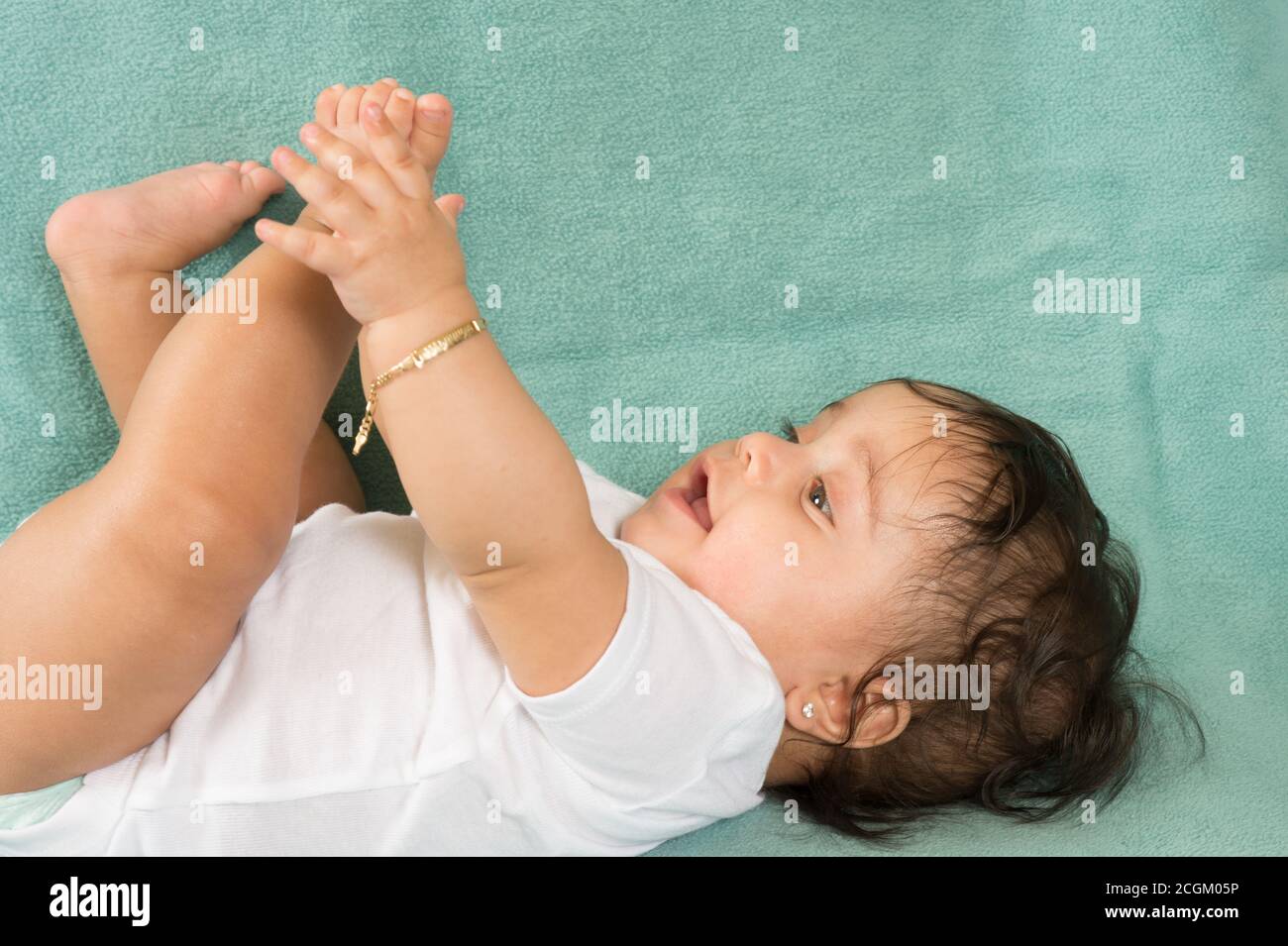 6 month old baby girl on back close up reaching for foot, wearing good ...