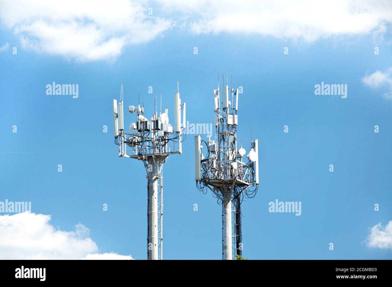 Two telecommunication towers with radio modules and antennas against a background of blue sky ...