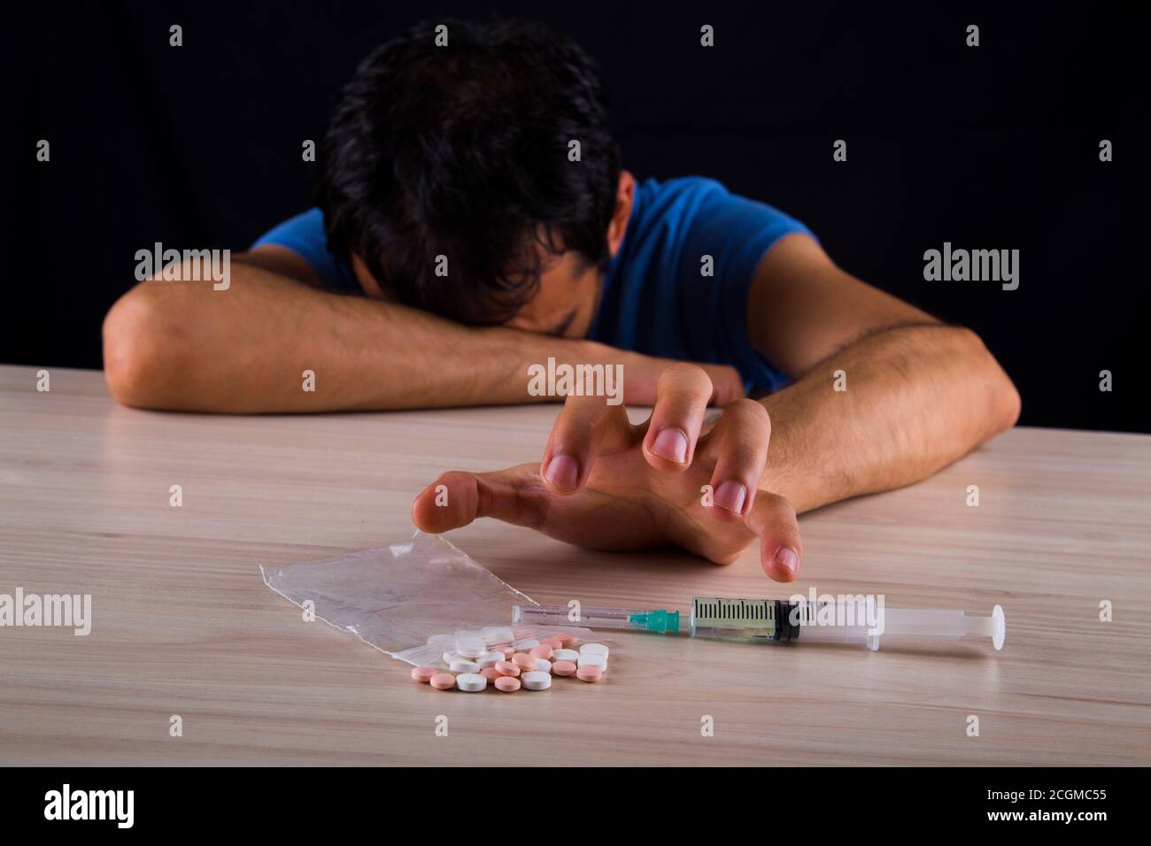 Male drug addict sitting with syringe and drugs out of focus in ...