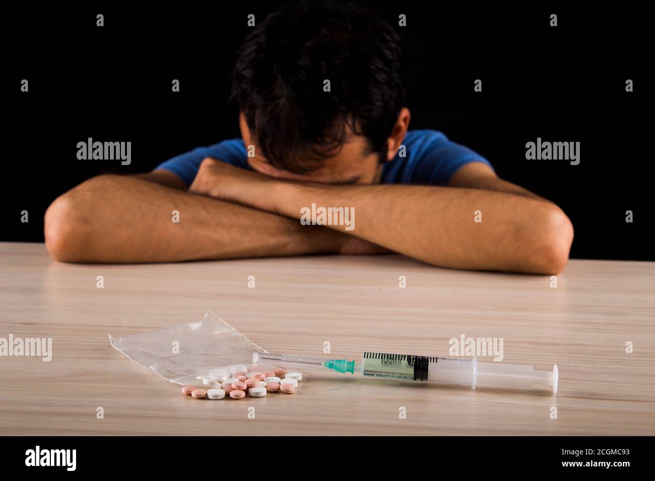 Male drug addict sitting with syringe and drugs out of focus in ...